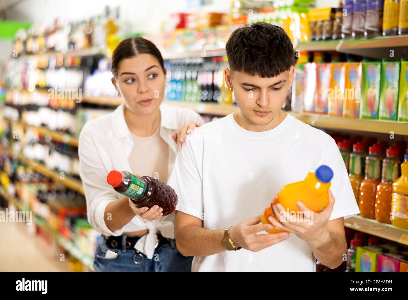 Positive young couple choosing drinks in grocery store Stock Photo - Alamy