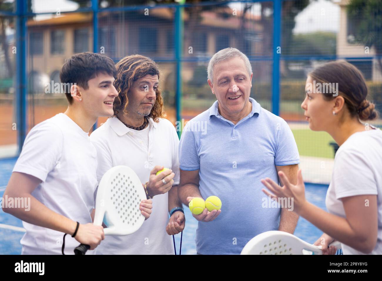 Two pairs with rackets in their hands chatting after playing padel on ...