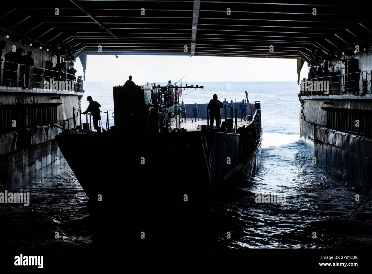 U.S. Navy Sailors guide landing craft utilities out of the well deck of ...