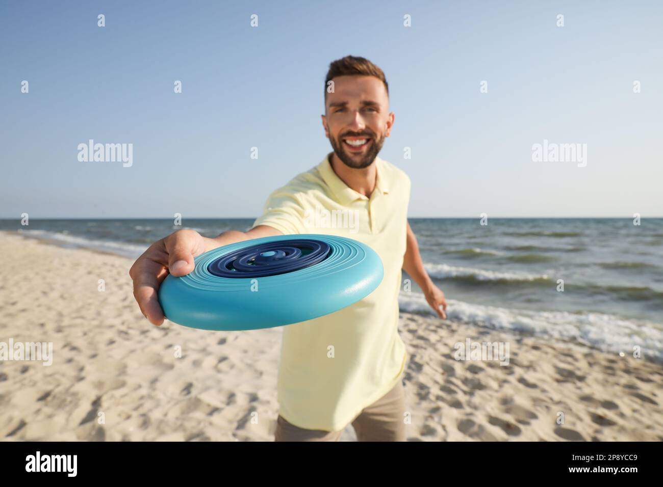Happy man throwing flying disk at beach, focus on hand Stock Photo - Alamy