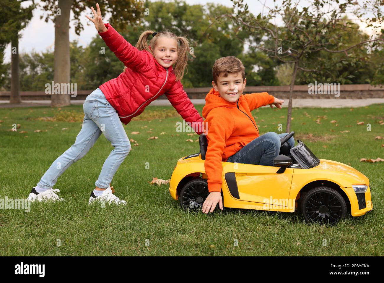 Cute girl pushing children's car with little boy in park Stock Photo ...
