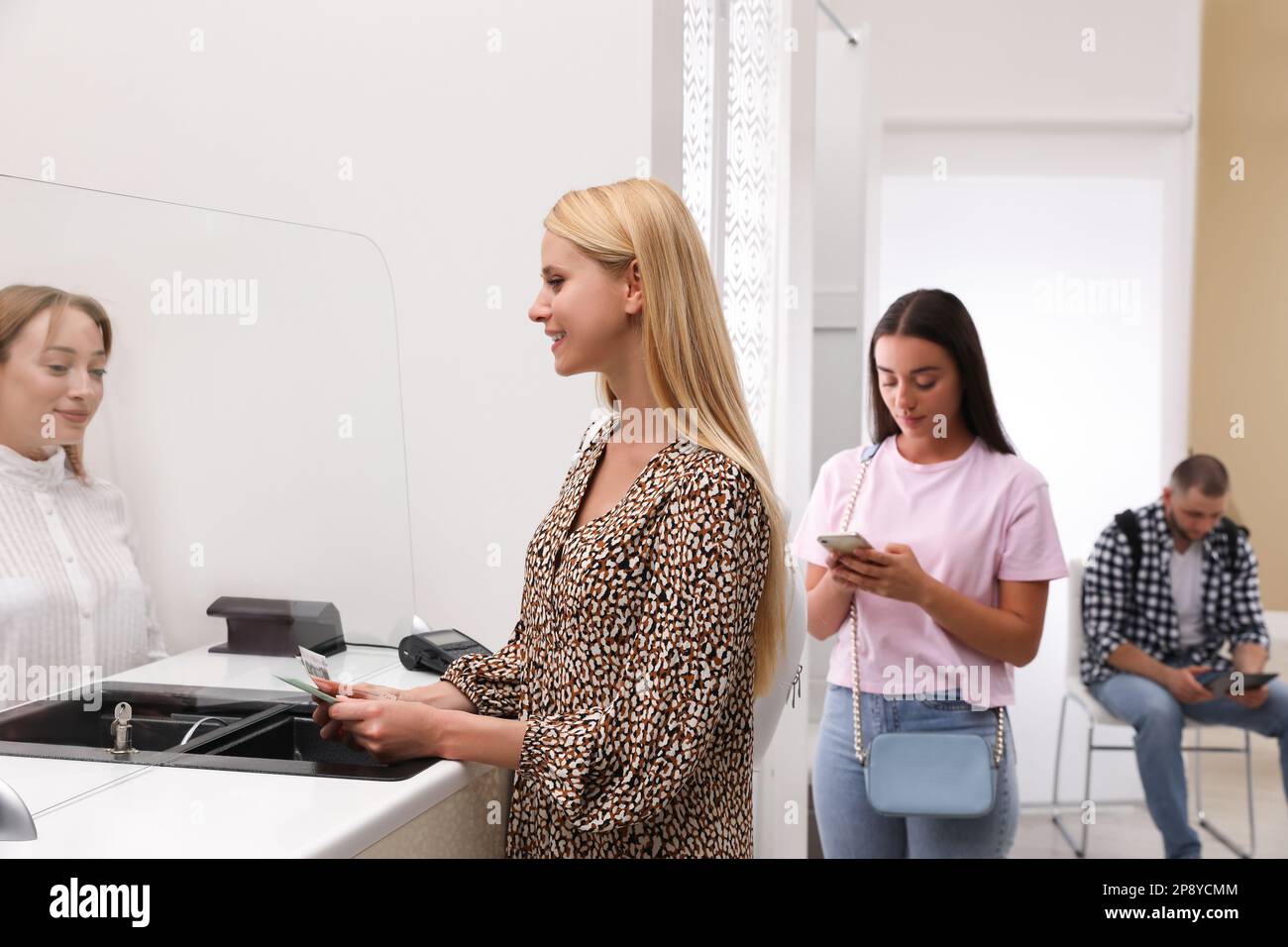 Woman with money and other people in line at cash department window. Currency exchange Stock ...