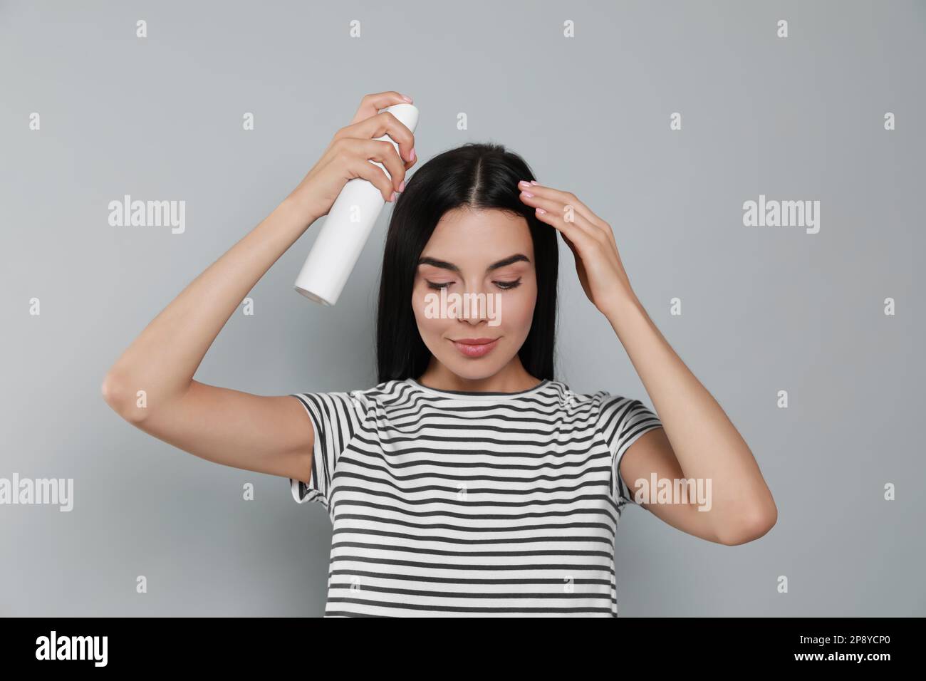Woman applying dry shampoo onto her hair on light grey background Stock ...