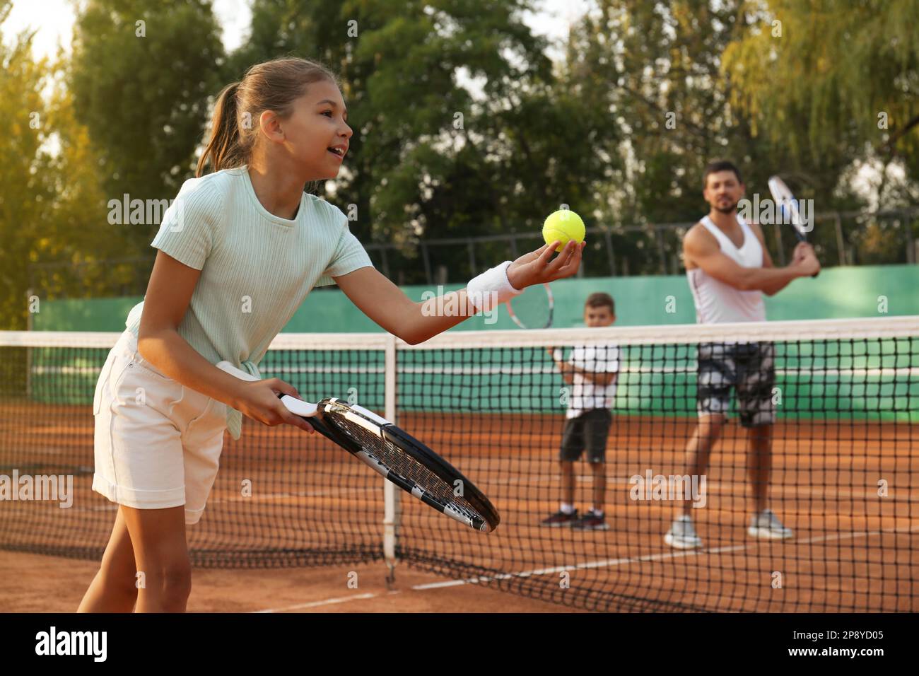 Happy family playing tennis on court outdoors Stock Photo - Alamy