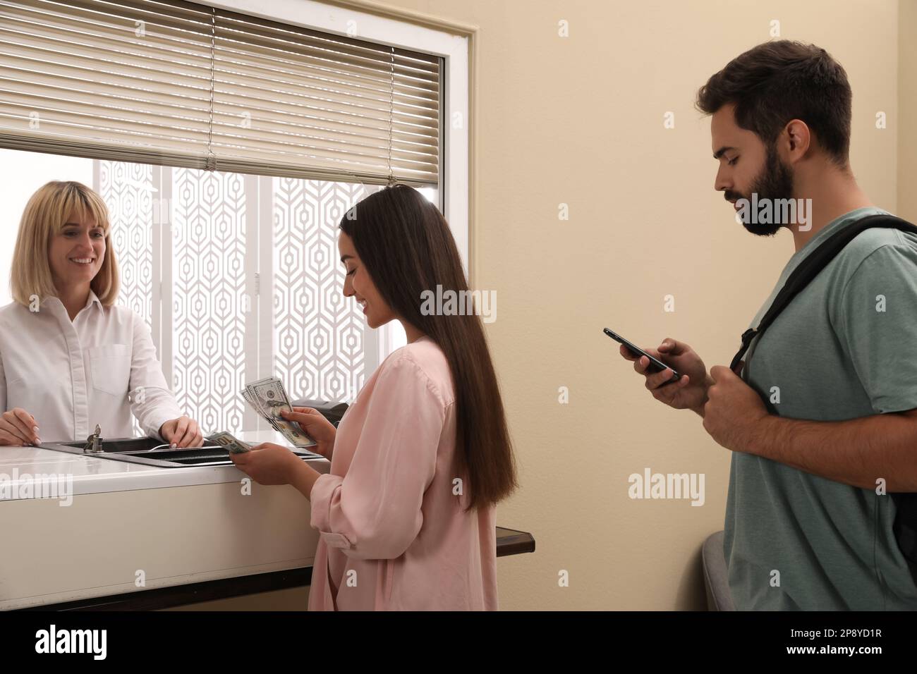 Young woman with money at cash department window in bank. Currency ...