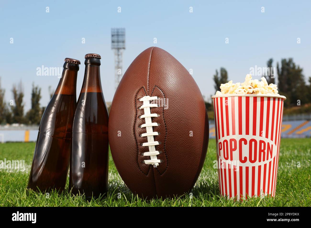 American football ball with beer and popcorn on green field grass in ...