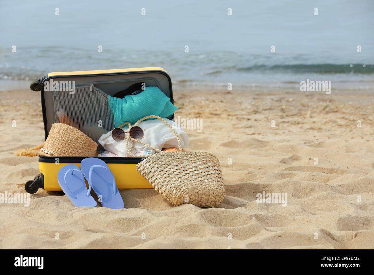 Open suitcase with beach items on sandy seashore, space for text Stock ...