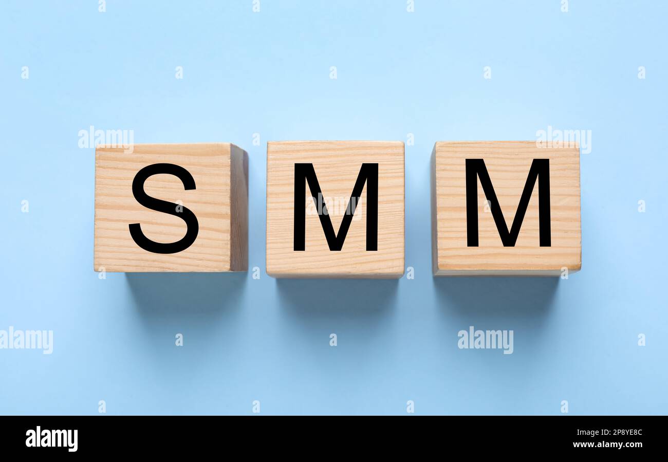 Wooden cubes with abbreviation SMM (Social media marketing) on light ...