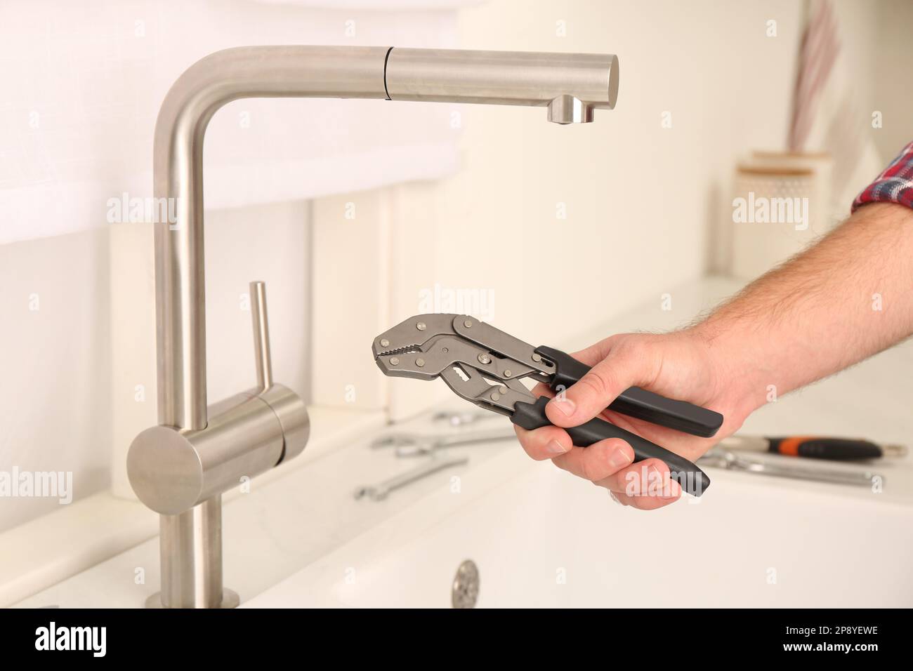 Man with wrench near sink in kitchen, closeup. Water tap installation ...