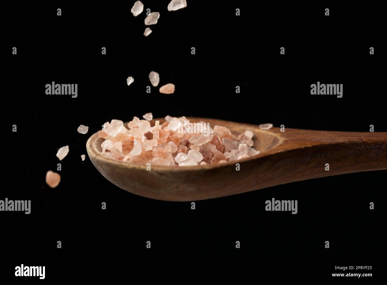A close up photo a coarse pink himalayan sea salt falling down on the ...
