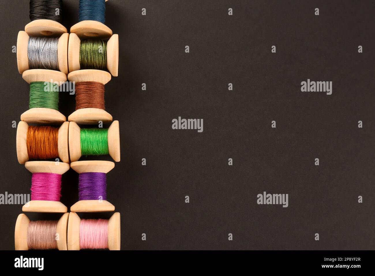 Different sewing threads on black background, flat lay. Space for text ...