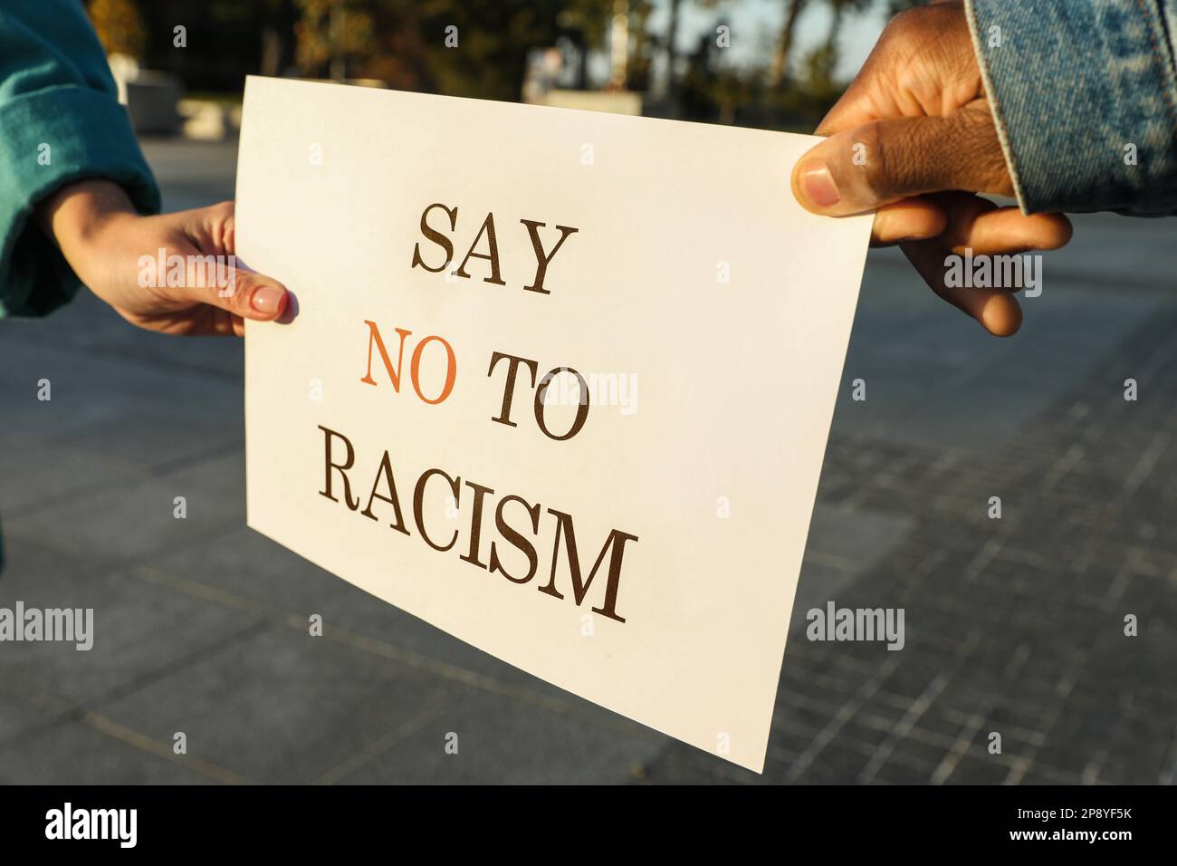 Woman and African American man holding sign with phrase Say No To ...