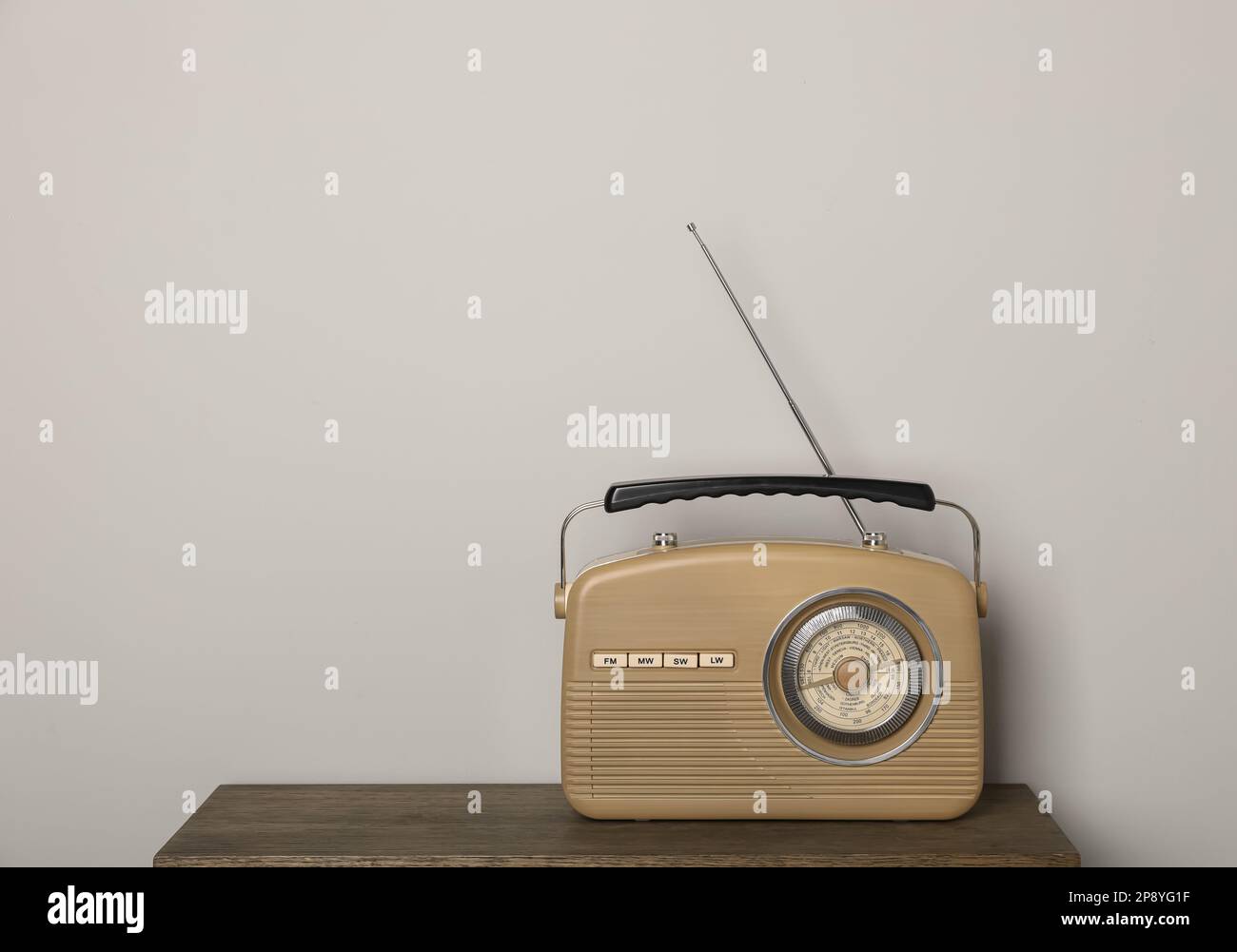 Retro radio receiver on wooden table against light grey background ...