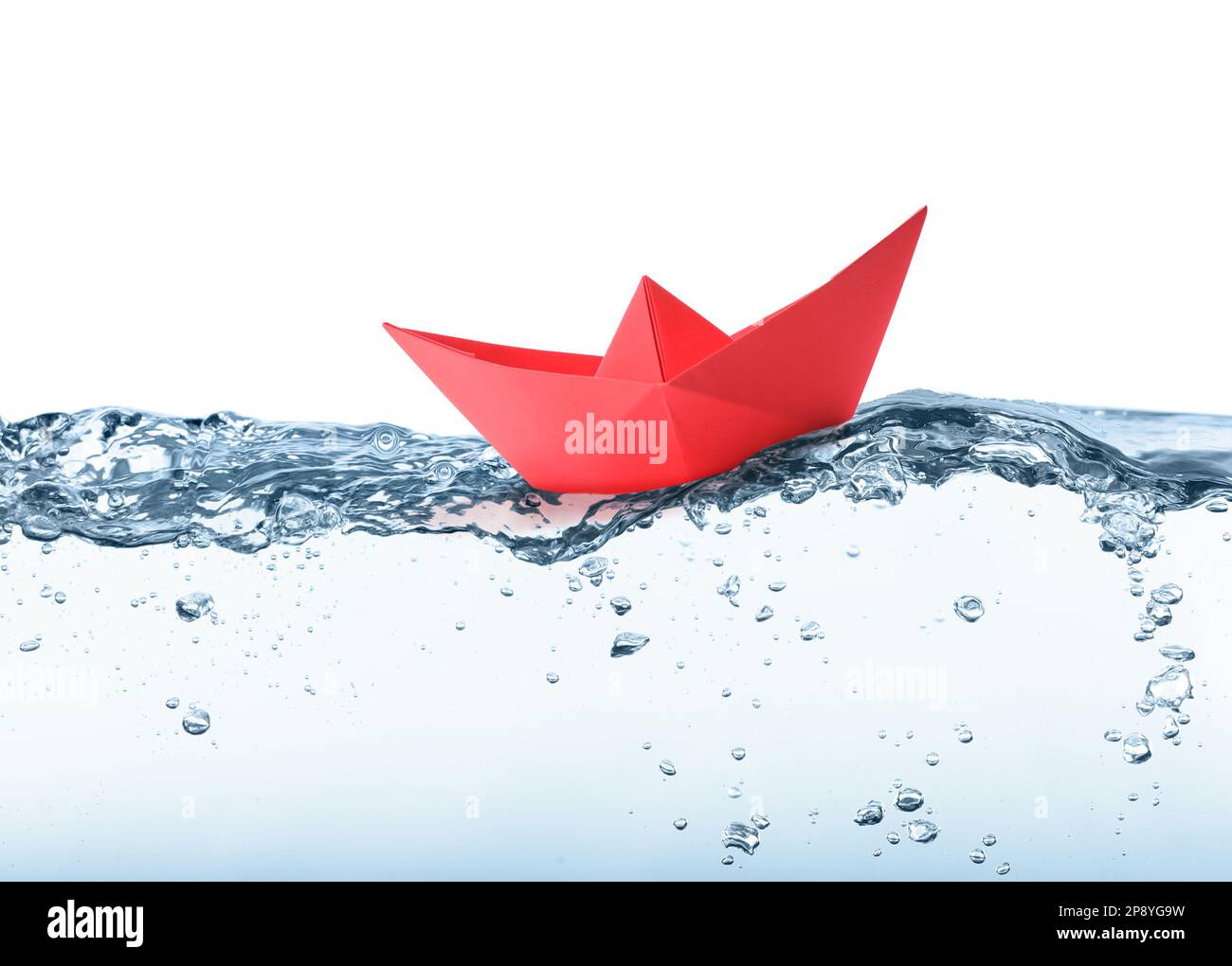 Handmade red paper boat floating on clear water against white ...