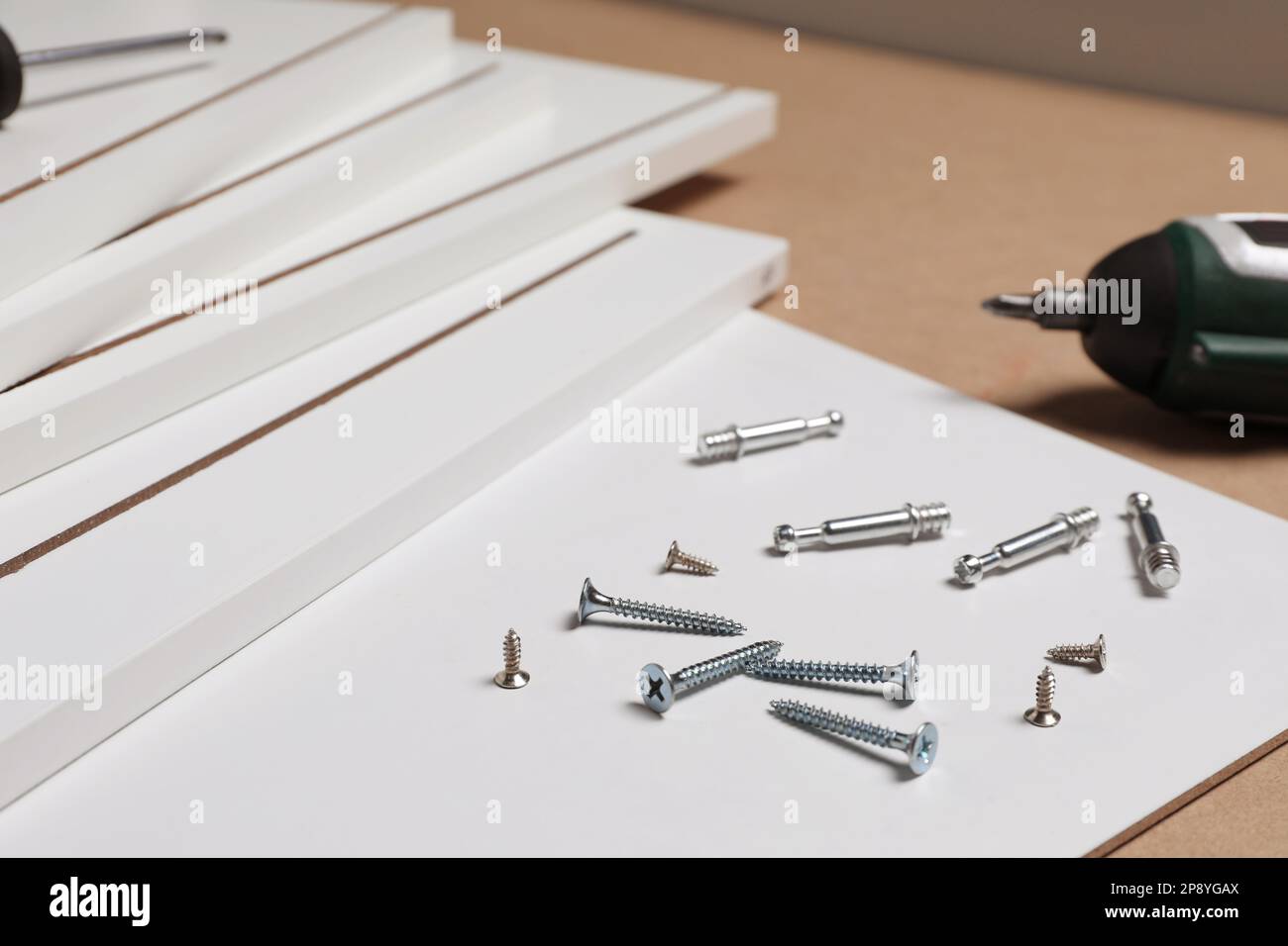 White furniture assembly parts and different metal fasteners on brown ...
