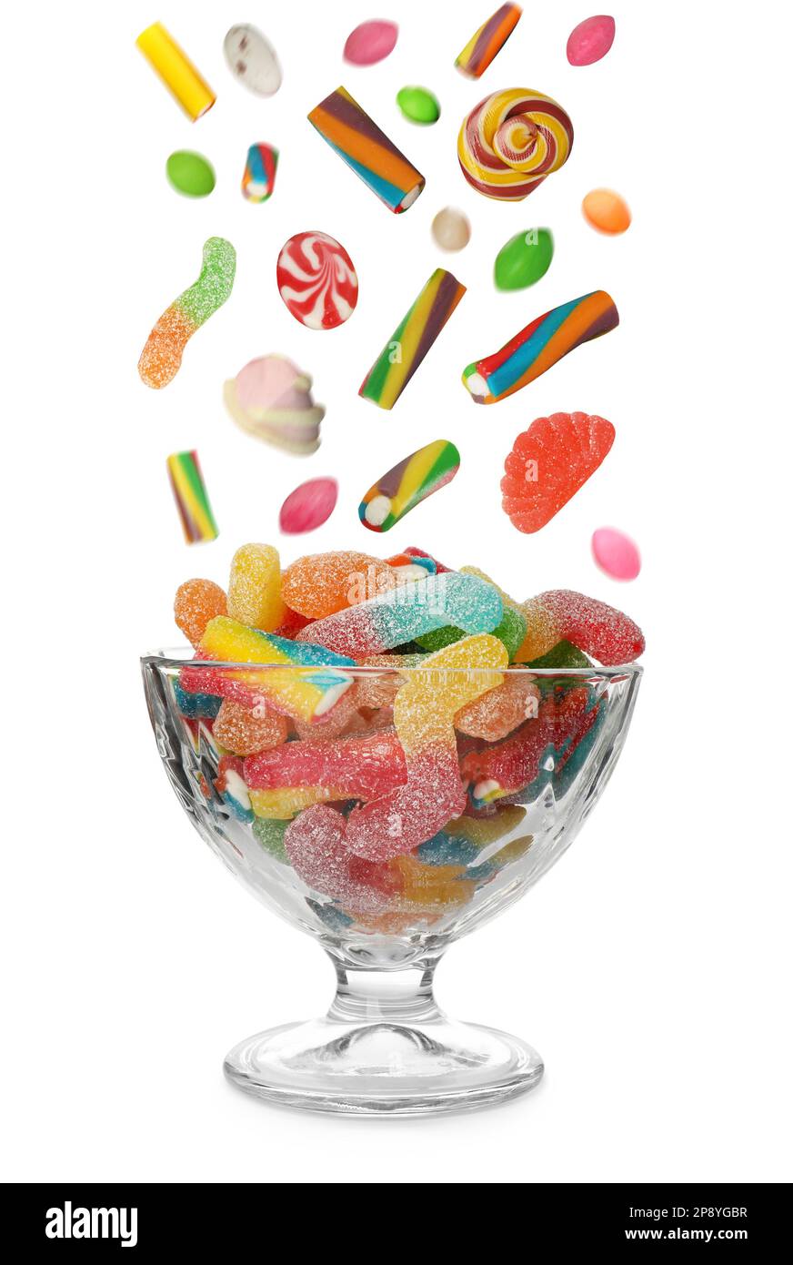 Different delicious candies falling into glass dessert bowl on white ...