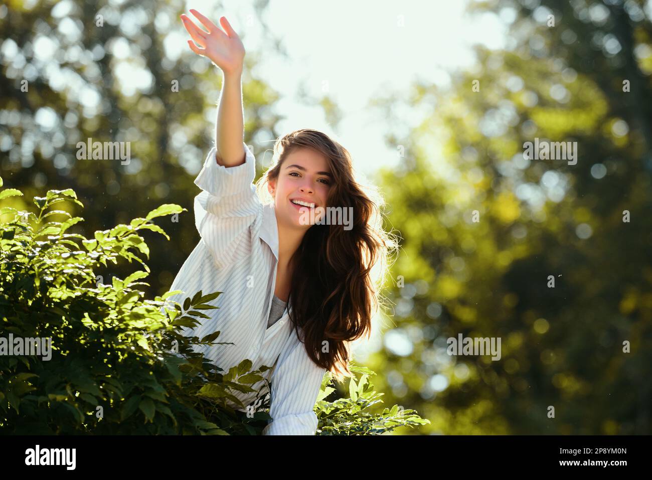 Friendly woman saying hello greetings on nature background in summer or ...