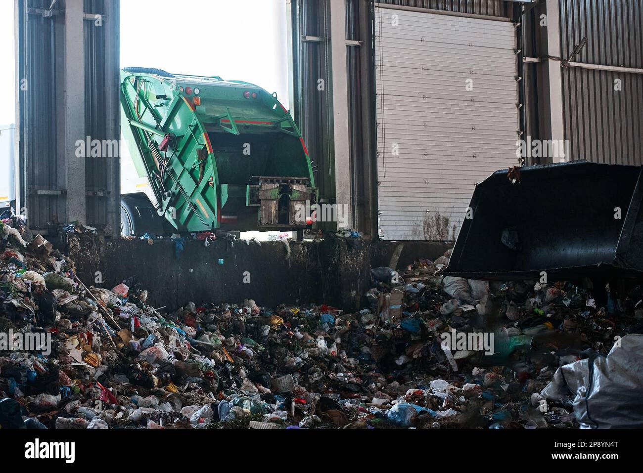 A garbage truck unloads household waste in the receiving chamber of a ...