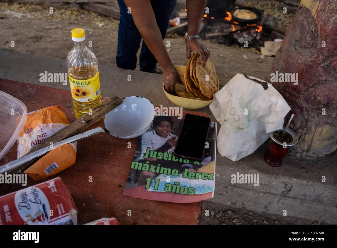 A woman prepares a meal next to a flyer with a portrait of Maximo Jerez ...