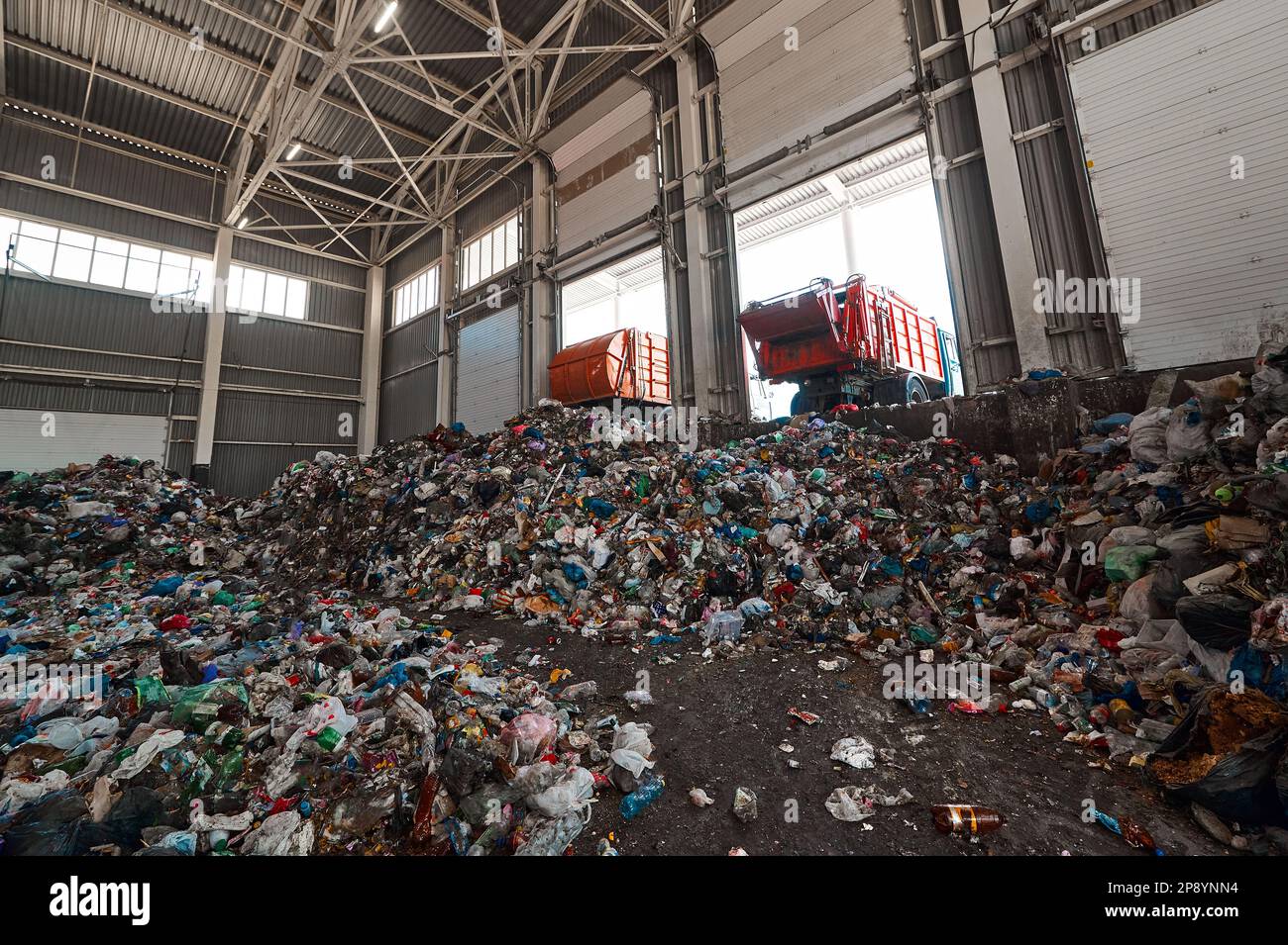 Garbage truck unloads household waste in the receiving chamber of a ...