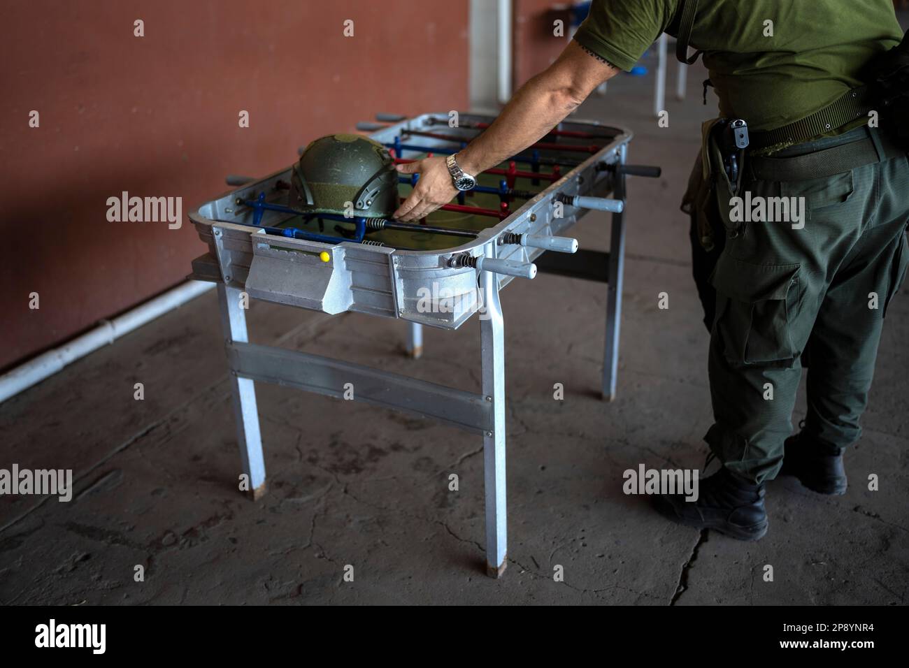 A border police agent reaches for his helmet on a foosball table before ...