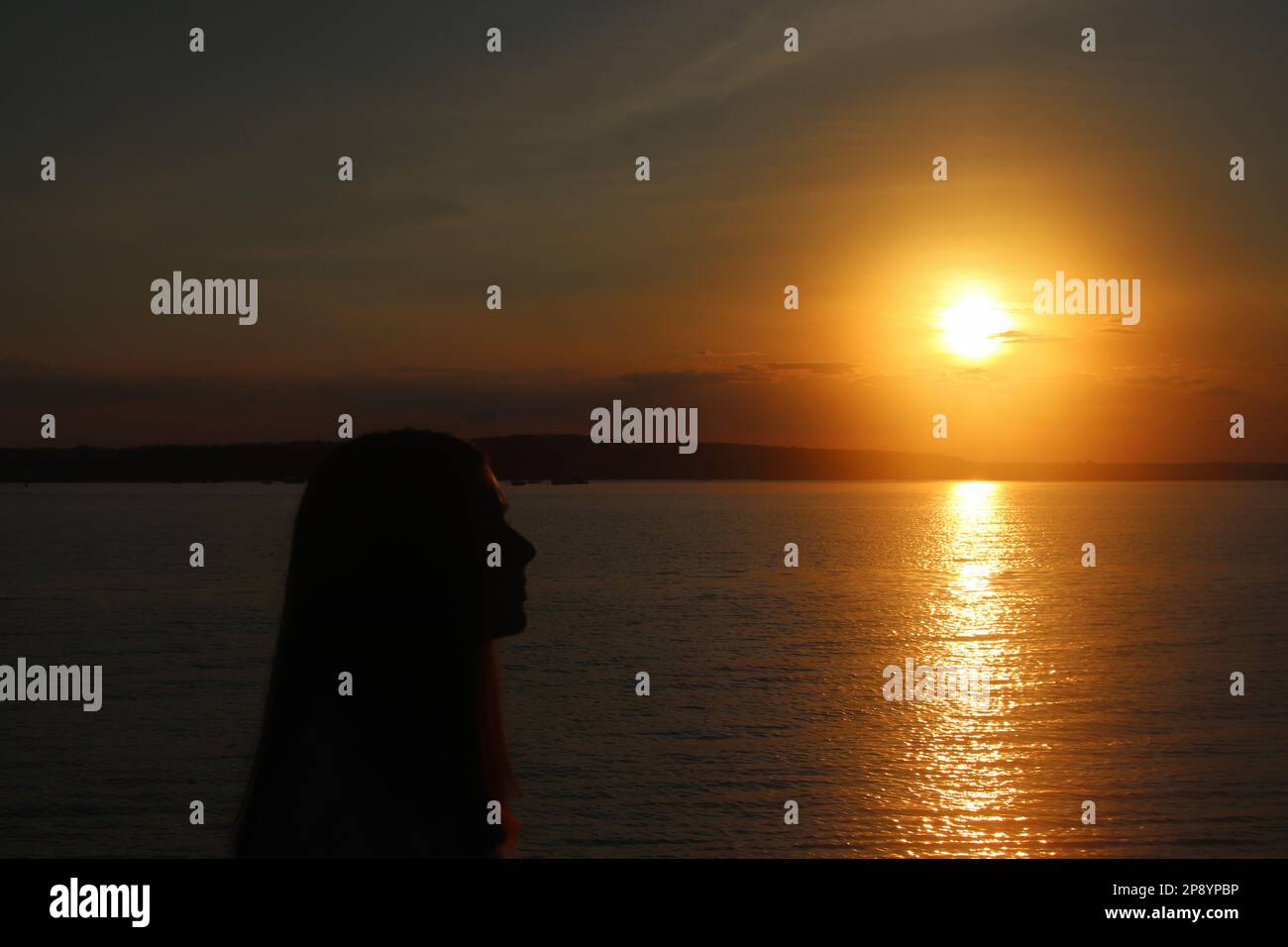 Silhouette of woman at beach during sunset facing away from camera ...