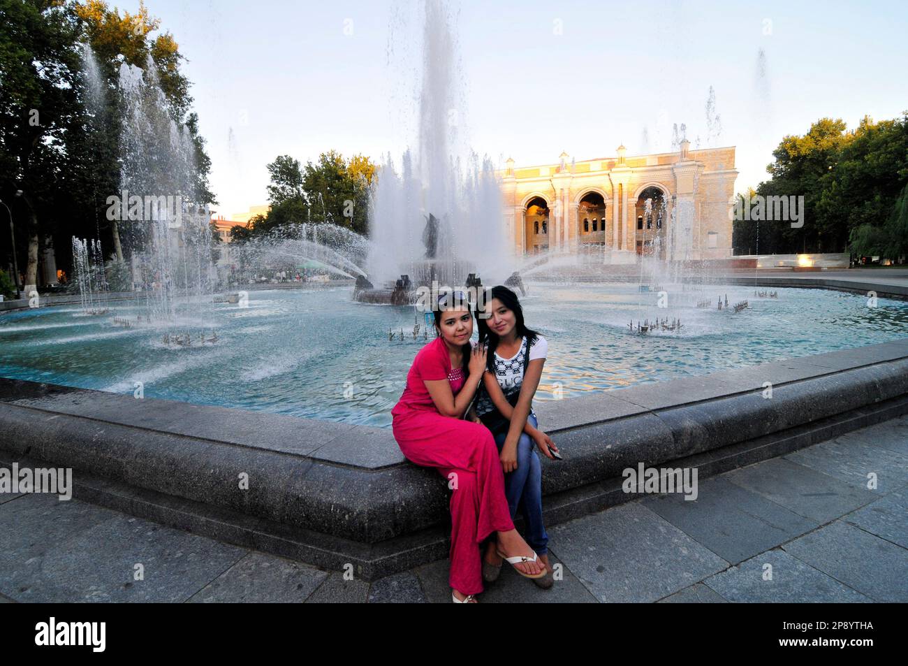 Uzbek teenage girls sitting by the water fountain in front of the ...