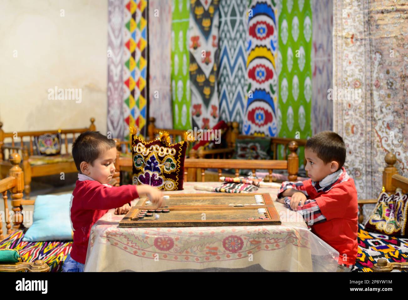 Young Uzbek kids playing backgammon at the old carpet bazaar in the old ...