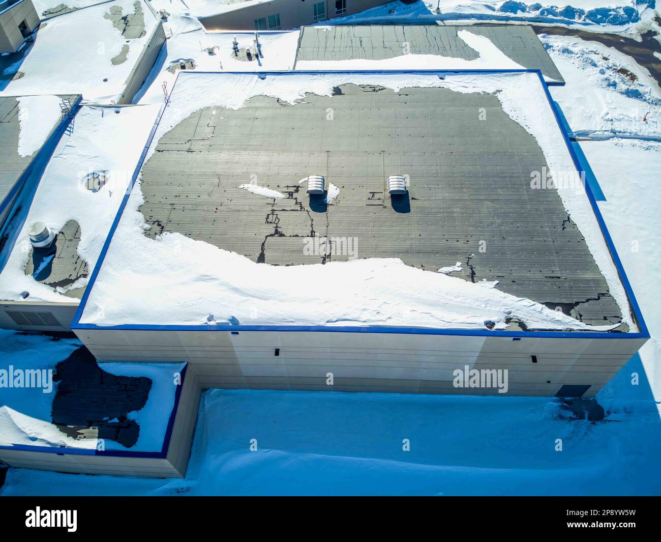 Elevated overhead drone view of a flat roofed building with snow load ...