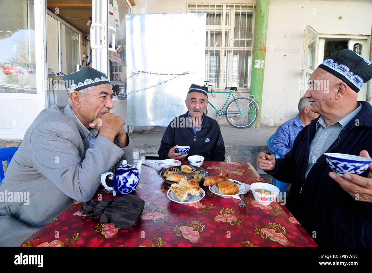 Uzbek men drinking tea and eating Samsa in a traditional teahouse in ...