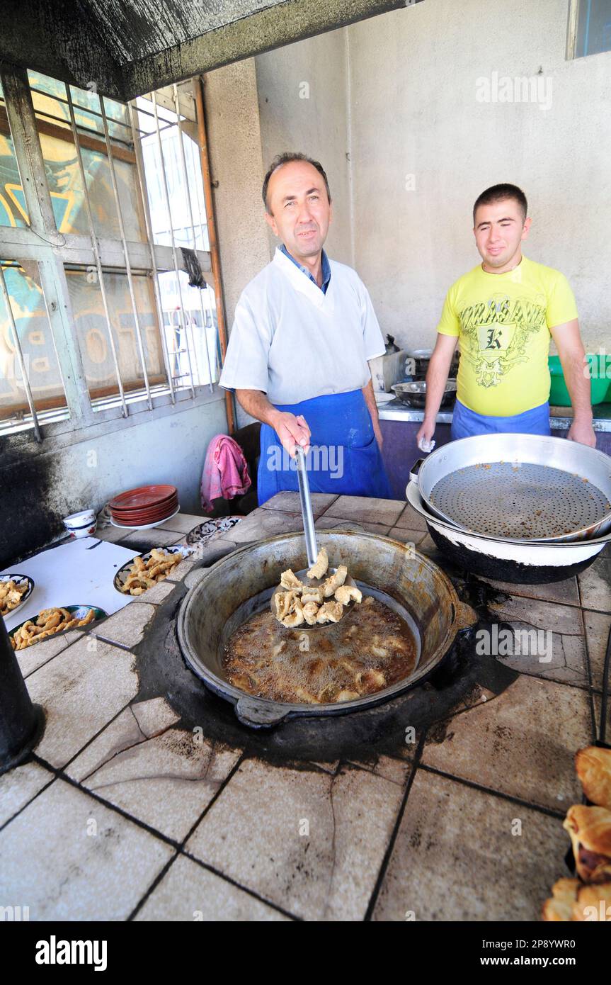 An Uzbek man frying dough in preparation of Baursaki, A traditional ...