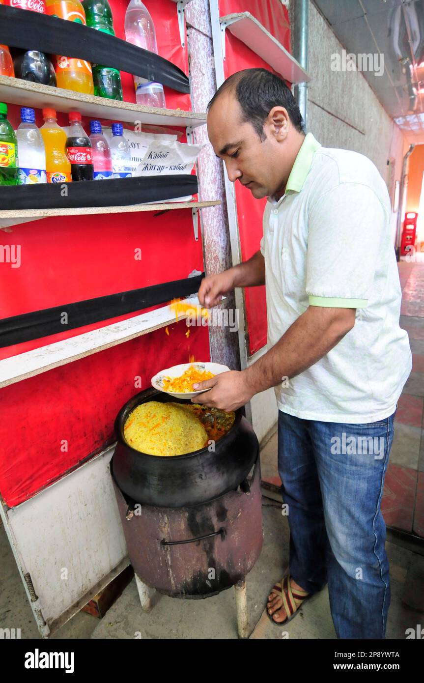 Plov is the national dish of Uzbekistan. An Uzbek man taking out Plov ...