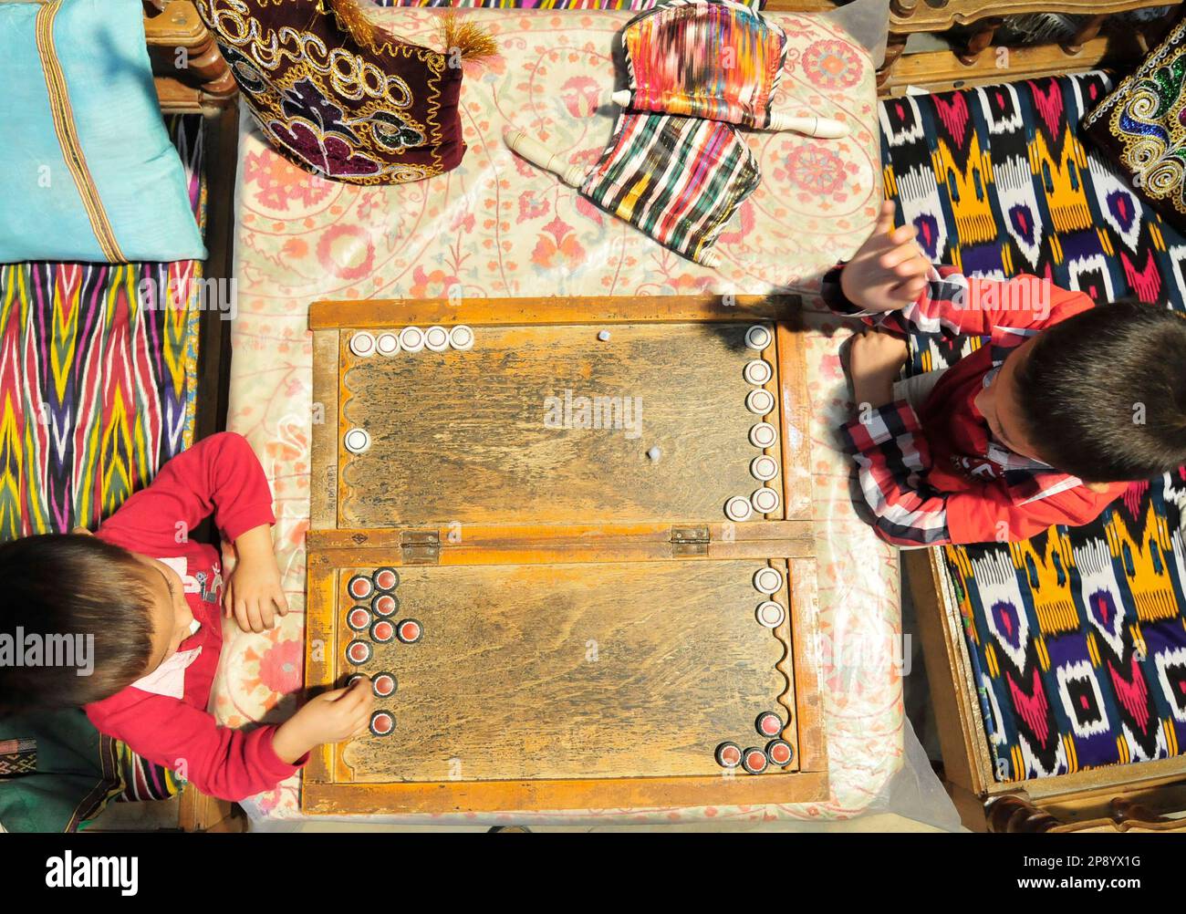 Young Uzbek kids playing backgammon at the old carpet bazaar in the old ...