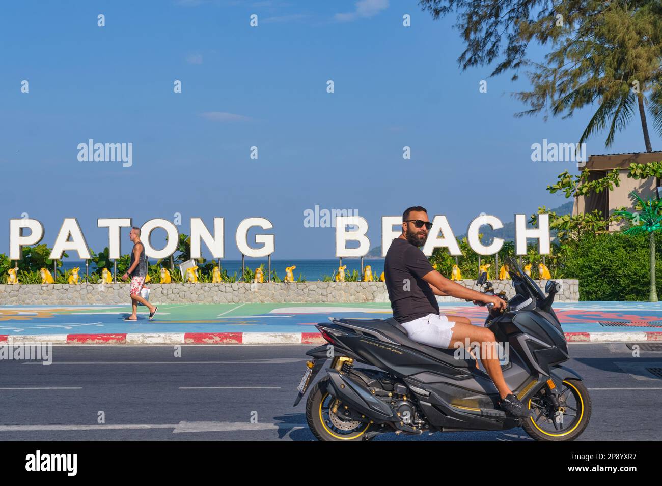 An Arab tourist rides his motorbike past the landmark "Phuket Beach" lettering at Patong beach ...