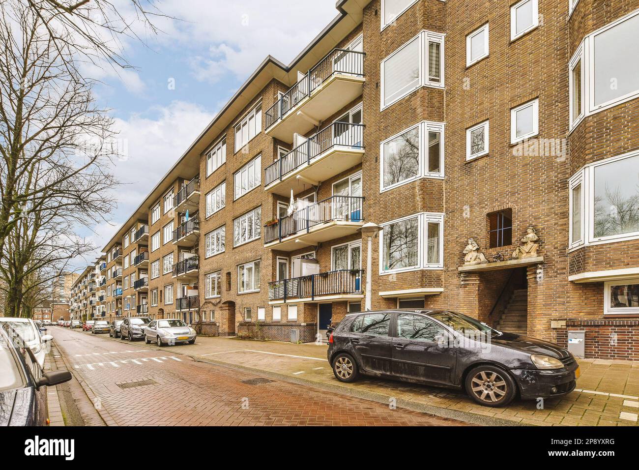 a car parked on the side of a street in front of a brick building with ...