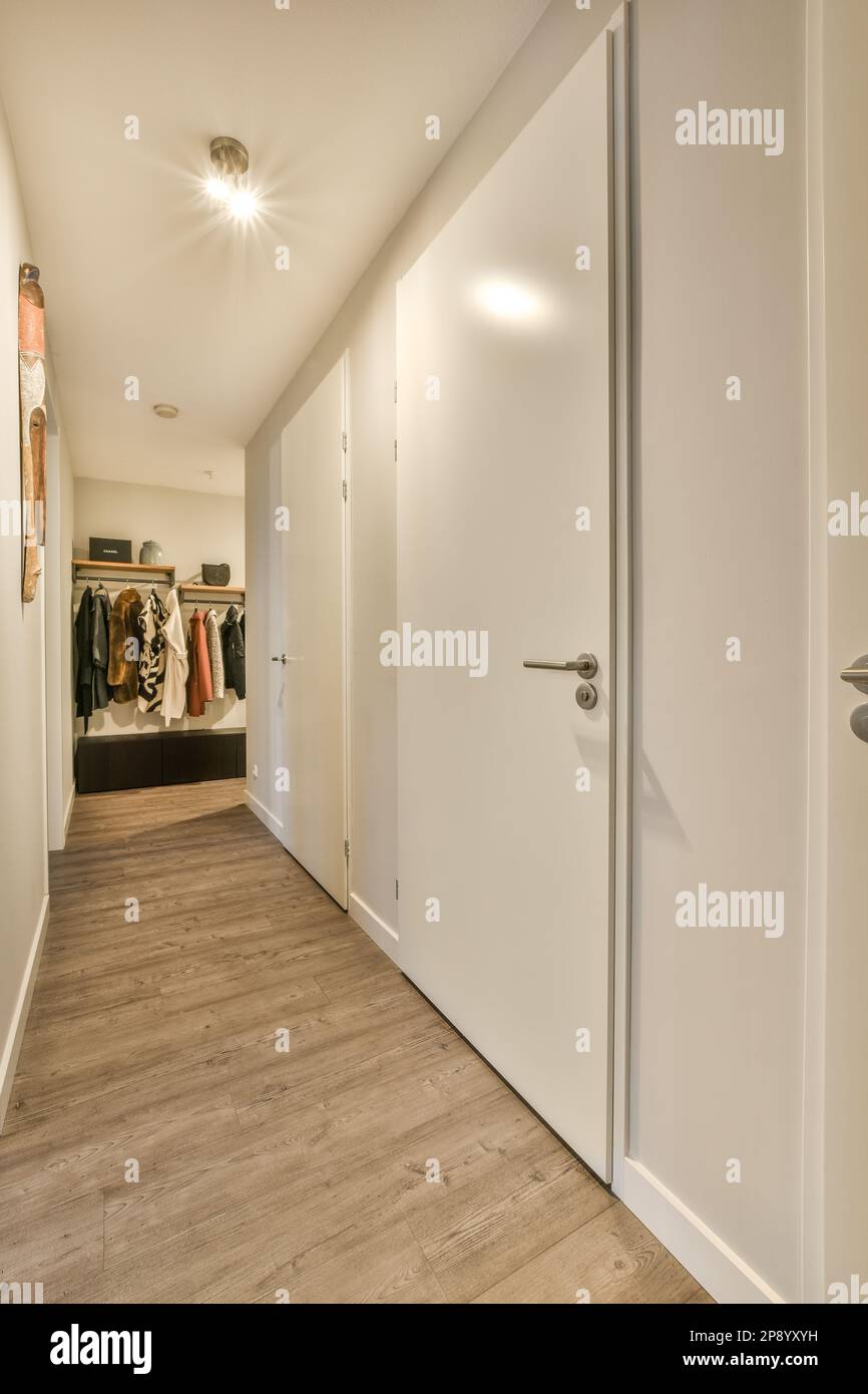 a hallway with white walls and wood flooring the room is well lit by ...