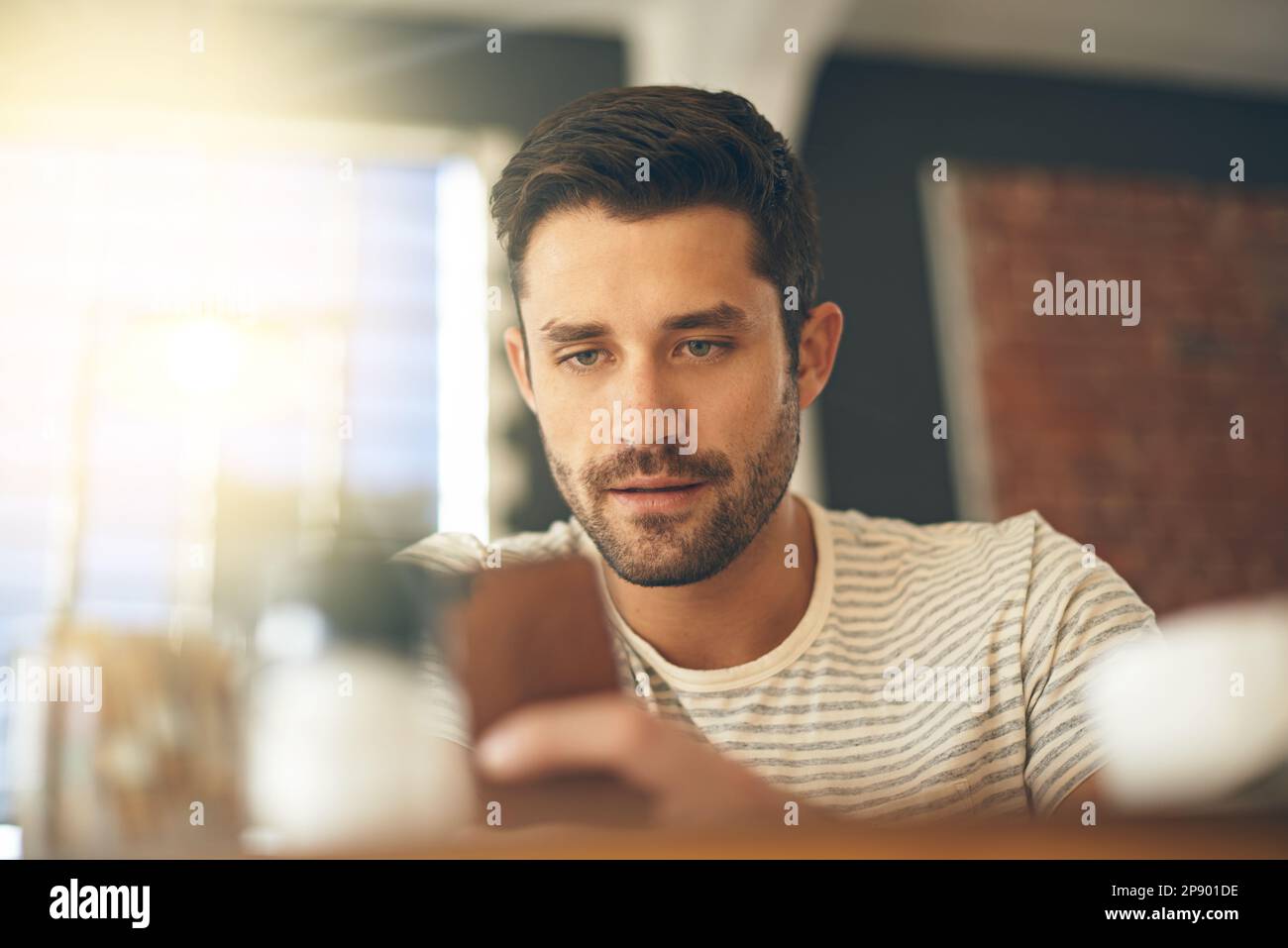 Checking his texts. a young man using his cellphone in a coffee shop ...