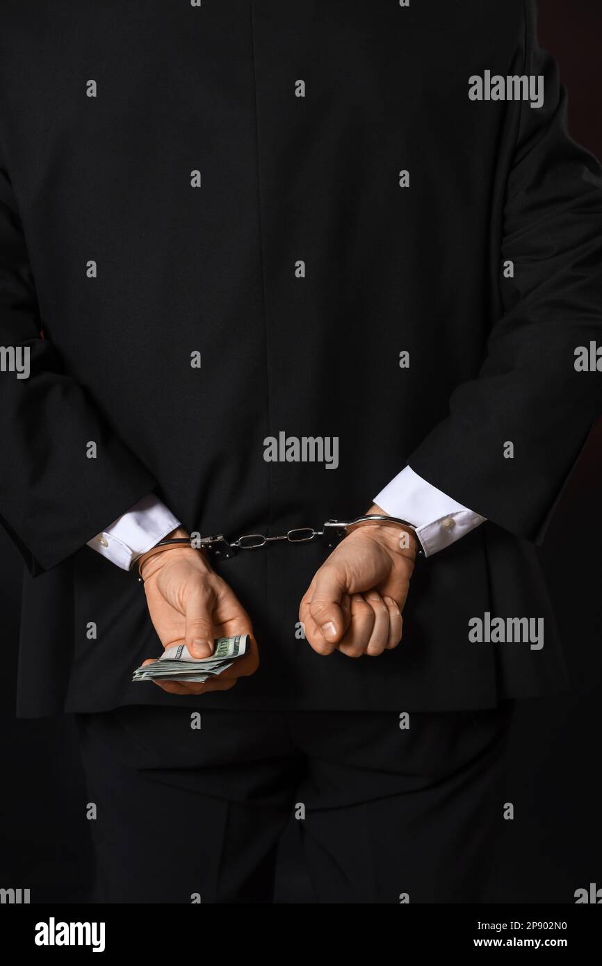 Handcuffed businessman with bribe on dark background, back view Stock ...