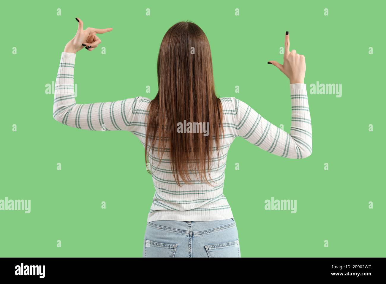 Young woman showing loser gesture on green background, back view Stock ...
