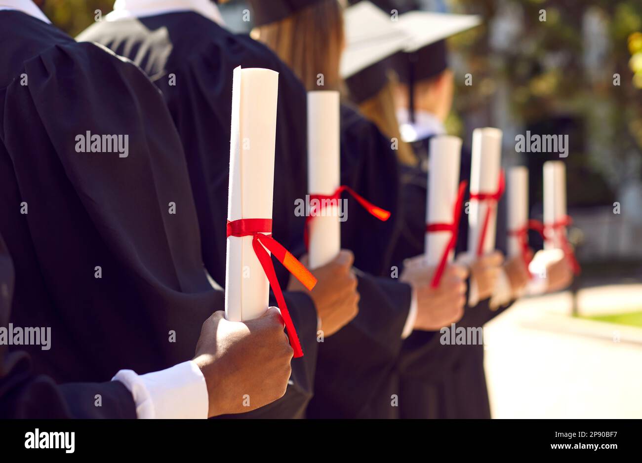 Diverse college or university graduates with diplomas at outdoor ...