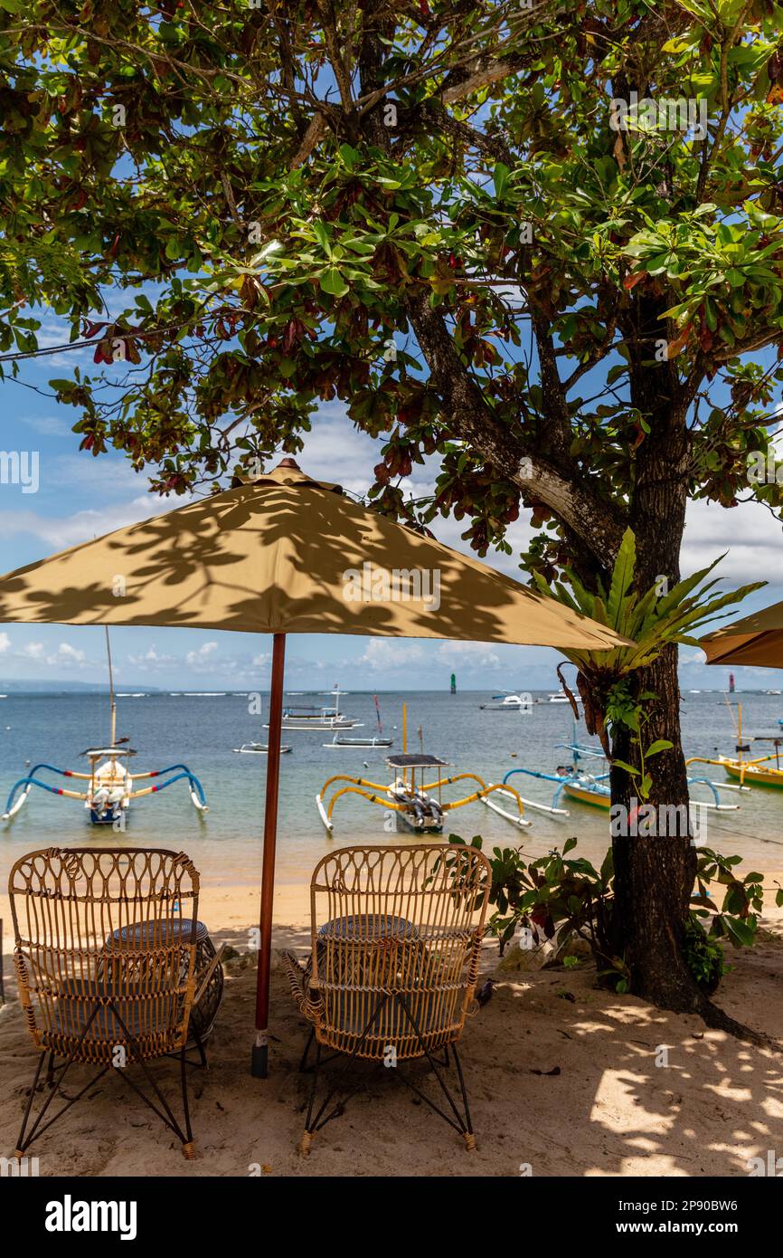 Views of Sanur beach, boats, ocean, trees. Cafe tables on the sand ...