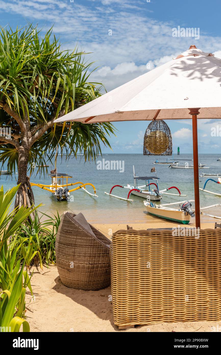 Views of Sanur beach, boats, ocean, trees. Cafe tables on the sand ...