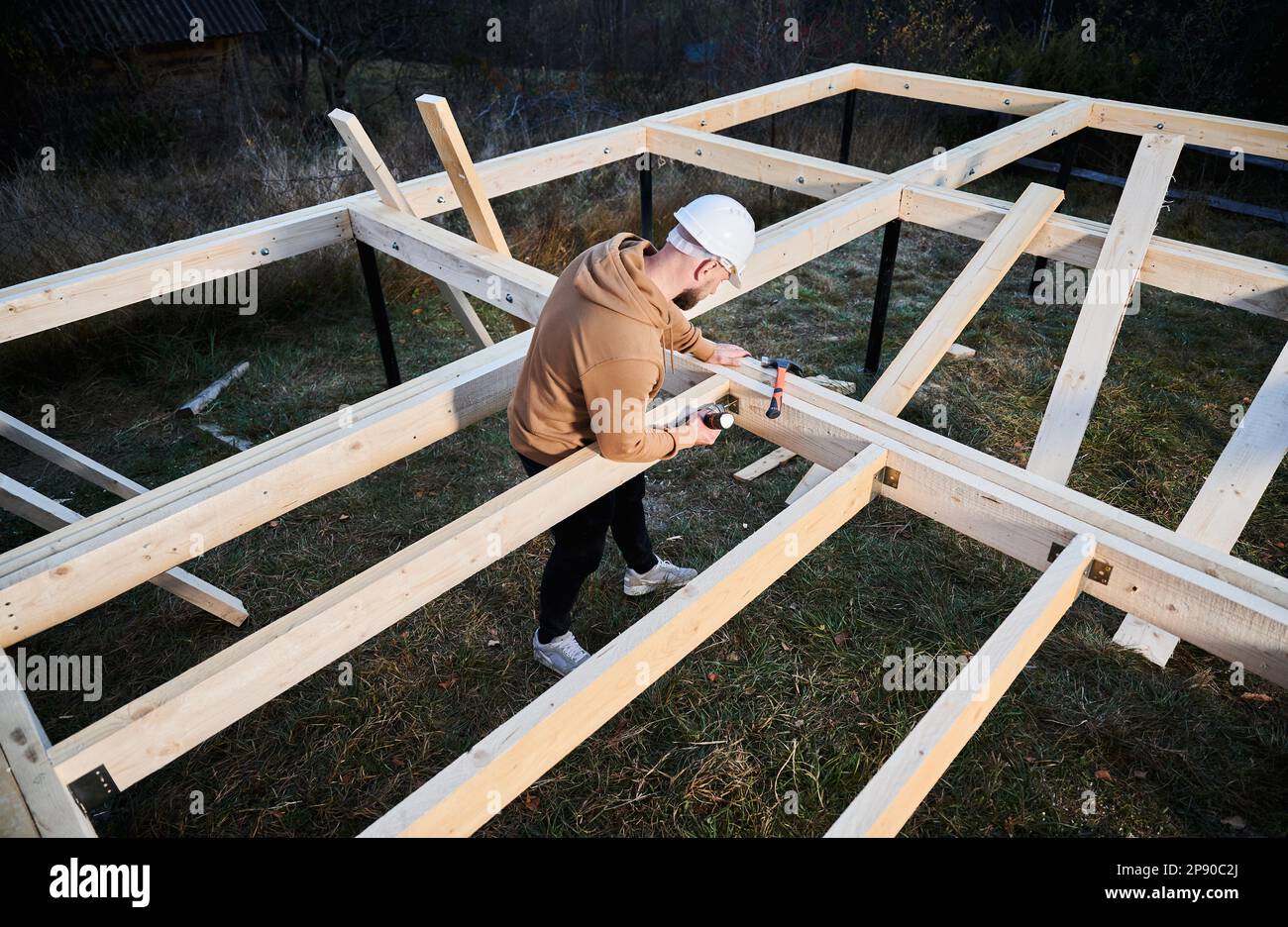 Man worker building wooden frame house on pile foundation. Carpenter ...