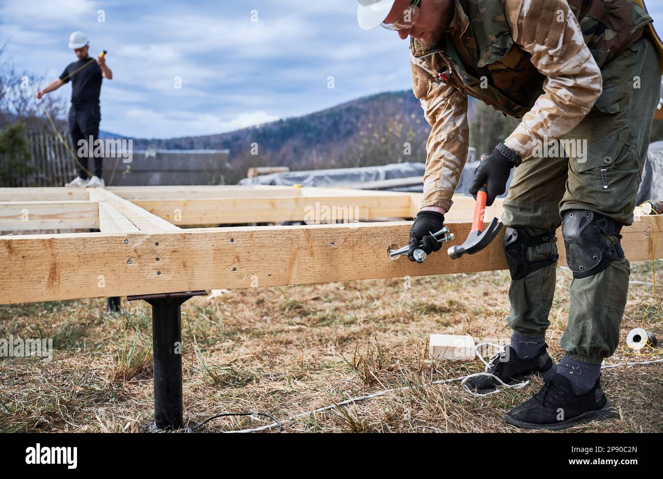 Man worker building wooden frame house on pile foundation. Carpenter ...