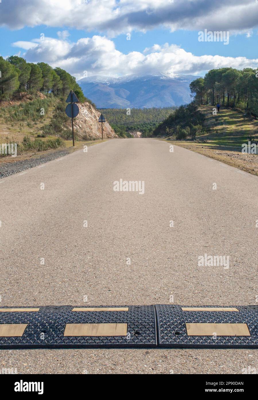 Speed bumps installed a local country road. Snowy mountains background ...
