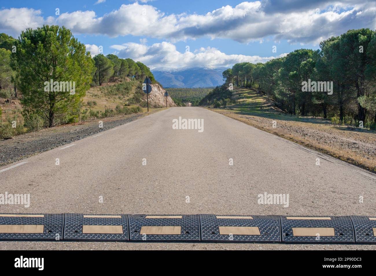 Speed bumps installed a local country road. Snowy mountains background ...
