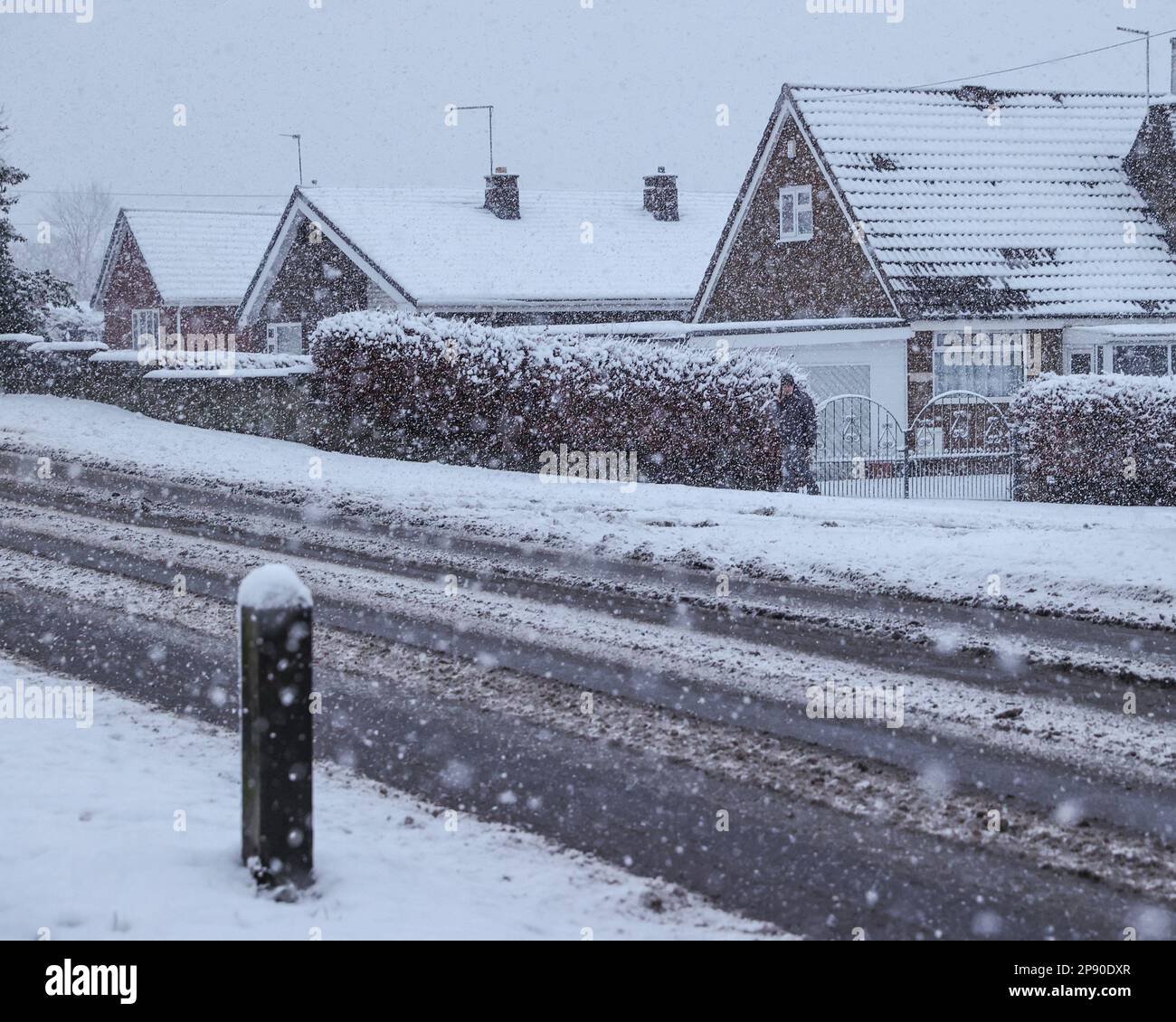 A person checks the main road as side streets are covered in heavy snow ...