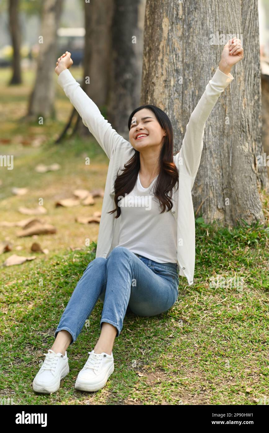 Happy young woman breathing fresh air while relaxing in the summer park ...