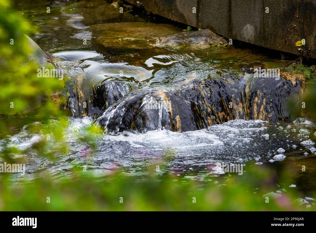 Closeup of flowing water over rocks in a garden water system Stock ...