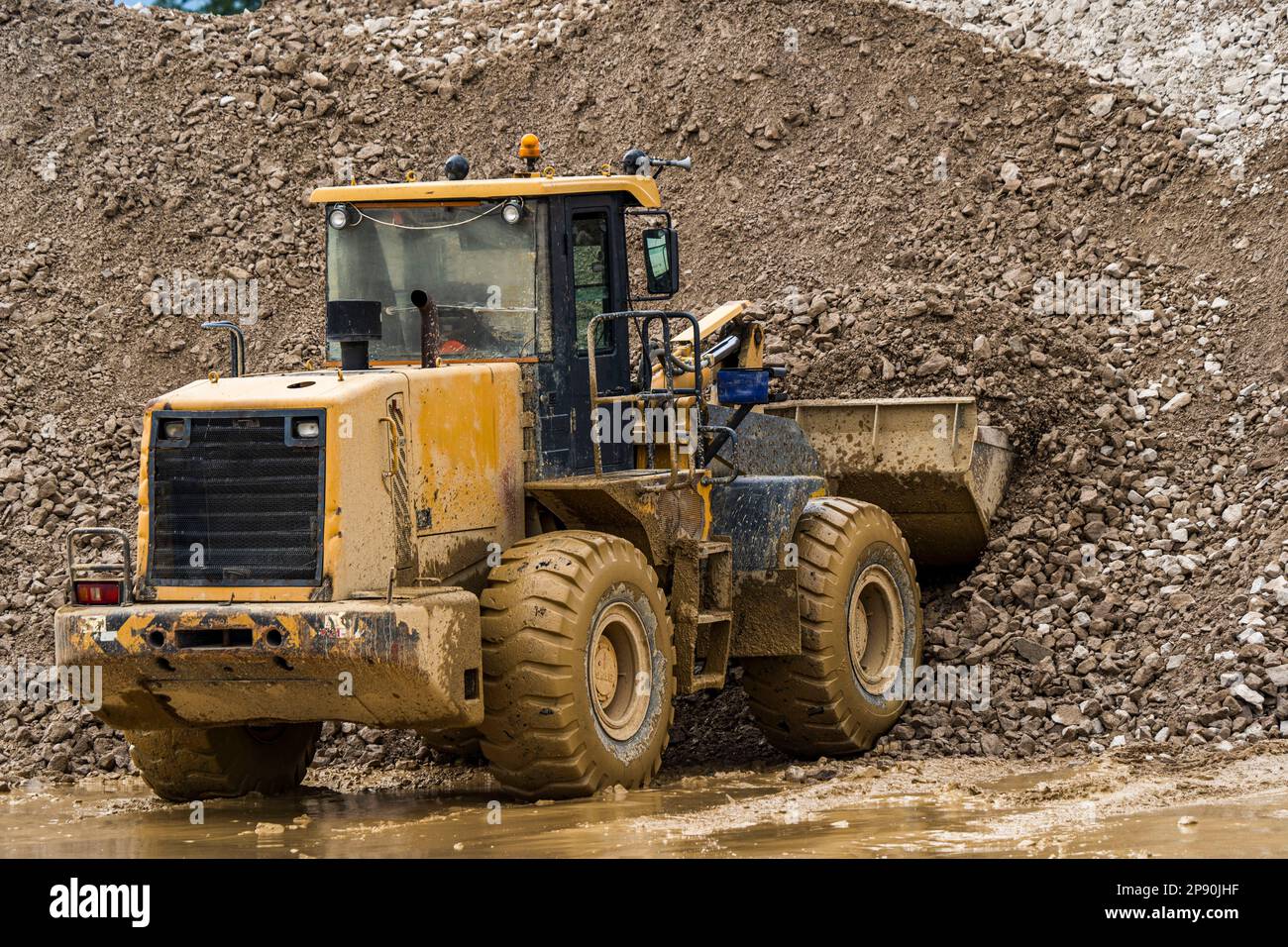 Front end loader dumping stone and sand in a mining quarry Stock Photo ...